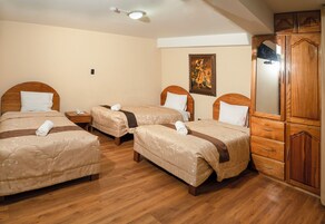 Quarto de hotel com três camas, guarda-roupa de madeira e um quadro na parede.