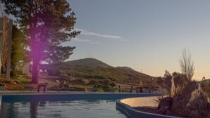 Piscina com vista para uma colina e uma árvore.