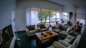 Uma sala de estar espaçosa, com uma janela grande, uma lareira e uma mesa de centro.