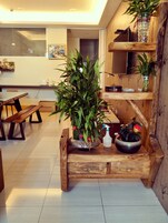 Uma cozinha moderna com armários de madeira, um espaço de refeições com um banco e uma grande planta em vaso.