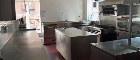 Cozinha moderna com eletrodomésticos de aço inoxidável, um relógio na parede e vista para o exterior.