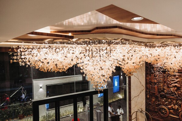 Um interior moderno com uma instalação no teto de luminárias pendentes, um painel digital e uma parede decorativa.