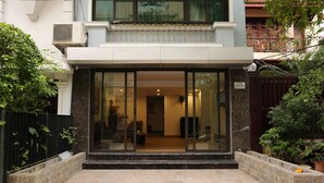 Um edifício moderno com entrada de vidro, um pátio pavimentado e uma pequena área de jardim.