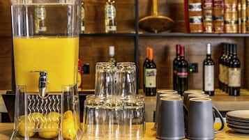 Uma área de bar com um jarro grande, copos, limões e garrafas de bebidas alcoólicas.