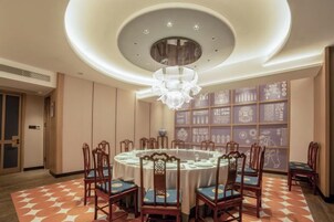 Uma mesa de jantar redonda com cadeiras, um candelabro e um papel de parede estampado.