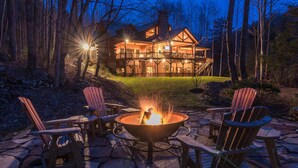 Uma cabana com lareira e cadeiras Adirondack na frente.