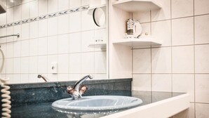 Casa de banho com lavatório de vidro, um porta-toalhas e um espelho.