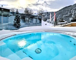 Piscina cercada por paisagem nevada e edifícios.
