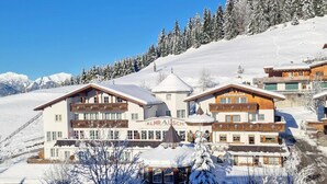 Um hotel com uma placa com a inscrição 'ALMR AUCH' em uma área montanhosa coberta de neve.