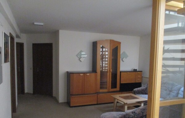Um quarto com um armário de madeira, uma mesa pequena e um sofá.