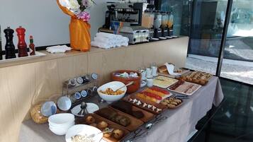Um buffet de café da manhã com diversas opções de alimentos, acompanhamentos e uma máquina de café.