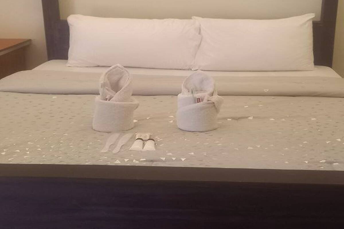 Cama bem arrumada com lençóis brancos e duas pequenas cestas sobre ela.