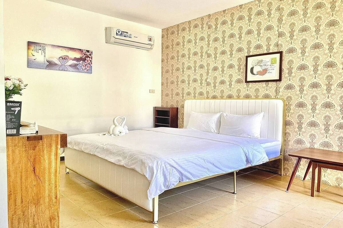 Quarto com cama, mesa de cabeceira, ar condicionado fixado na parede e papel de parede estampado.