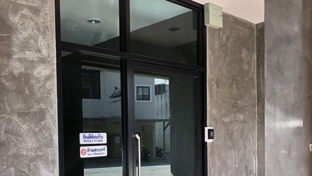 Uma entrada moderna com porta de vidro, tapete de boas-vindas e placa de proibido fumar.
