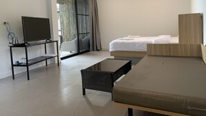 Quarto de hotel moderno com cama, televisão em móvel, mesinha e janela com cortinas.