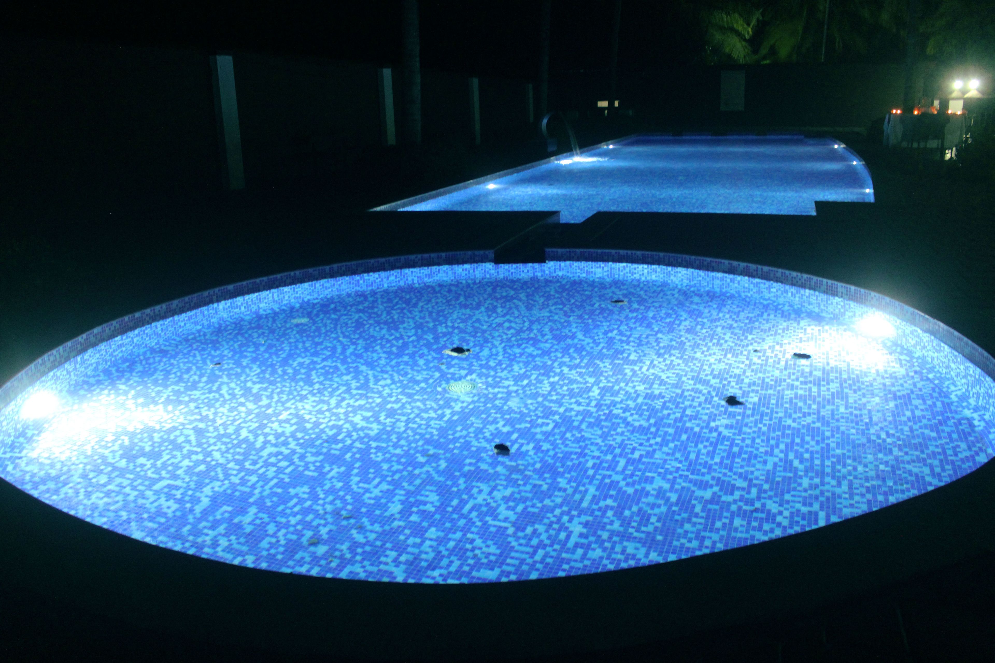 Piscina com padrão de azulejos azuis em mosaico e área de deck retangular.