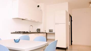 Um frigorífico, uma placa de cozinha, uma máquina de café expresso