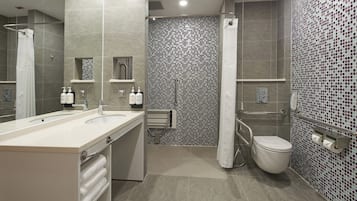 Uma casa de banho moderna com chuveiro, sanita e lavatório.