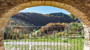 Estrutura de pedra arqueada com vista para uma encosta arborizada.