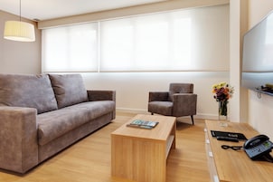 Uma sala de estar moderna com sofá, poltrona, mesa de centro e televisão de tela plana.