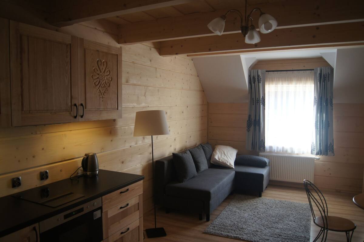 Um quarto acolhedor com decoração em madeira, um sofá, uma luminária e uma janela com cortinas.