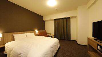 Quarto de hotel com uma cama grande, televisão, escrivaninha e uma cadeira.