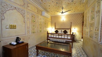 Quarto tradicional com cama, um armário de madeira e ventilador de teto.