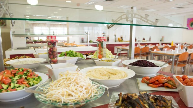 Buffet com diversos pratos, incluindo saladas, legumes e carnes grelhadas.
