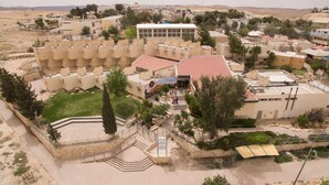 Albergue com um pátio central, vários edifícios e montanhas ao fundo.