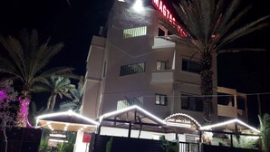 Um hotel com uma placa grande, várias varandas e iluminação externa.