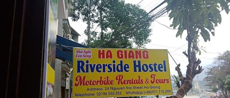 Placa do Ha Giang Riverside Hostel anunciando aluguel de motos e passeios.