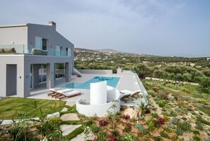 Uma casa moderna com piscina, espreguiçadeiras e jardim.