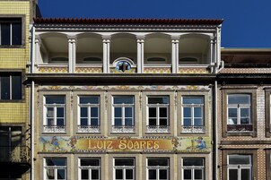 Um edifício com varanda, uma placa com o texto "LOIZ SOARES" e um mural colorido.