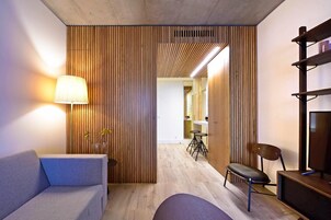 Uma sala de estar moderna com um sofá, uma luminária, uma TV e um divisória de madeira.