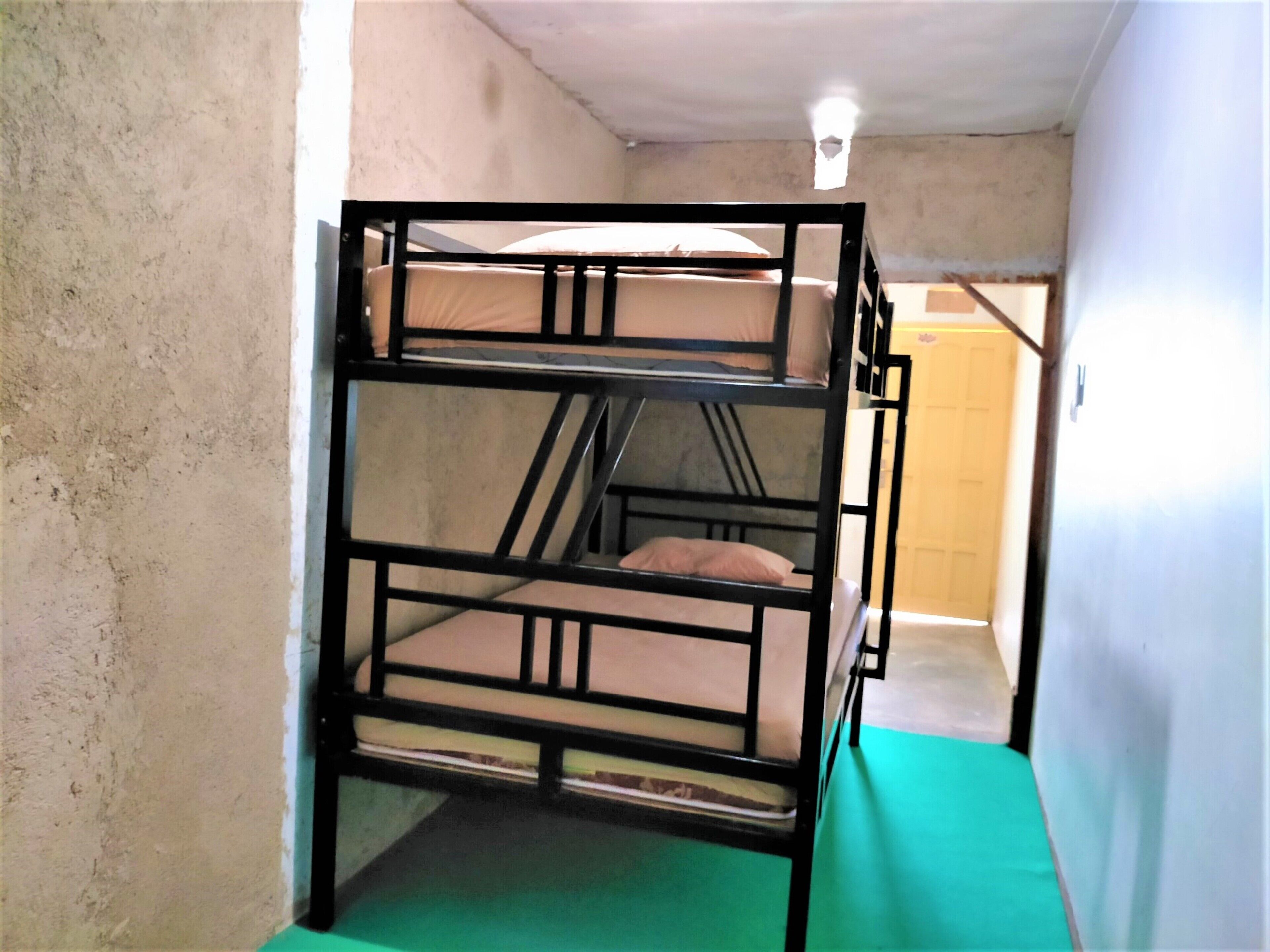 Uma cama beliche com um tapete verde no rodapé.