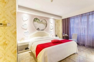 Quarto de hotel com cama, mesa de cabeceira, cadeira e janela com cortinas.