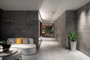 Um interior moderno com um sofá branco curvo, uma mesa redonda e plantas em vasos.