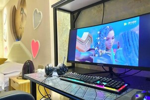 Uma estação de jogos com monitor, teclado e fones de ouvido em uma mesa.