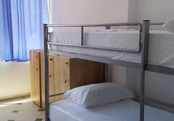 Quarto com beliche, um armário de madeira e janela com cortinas azuis.