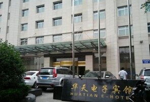 Entrada de um hotel com uma placa indicando 'HUATIAN E-HOTEL'.