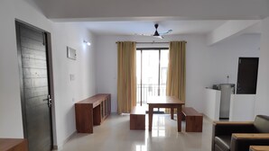 Uma sala de estar ampla com uma mesa de madeira, bancos, um sofá e um ventilador de teto.