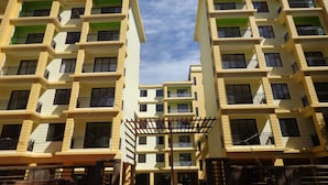 Edifício residencial com várias andares, varandas, um pátio central e céu claro.