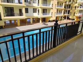 Um edifício com várias andares, varandas, piscina e chão em mosaico.