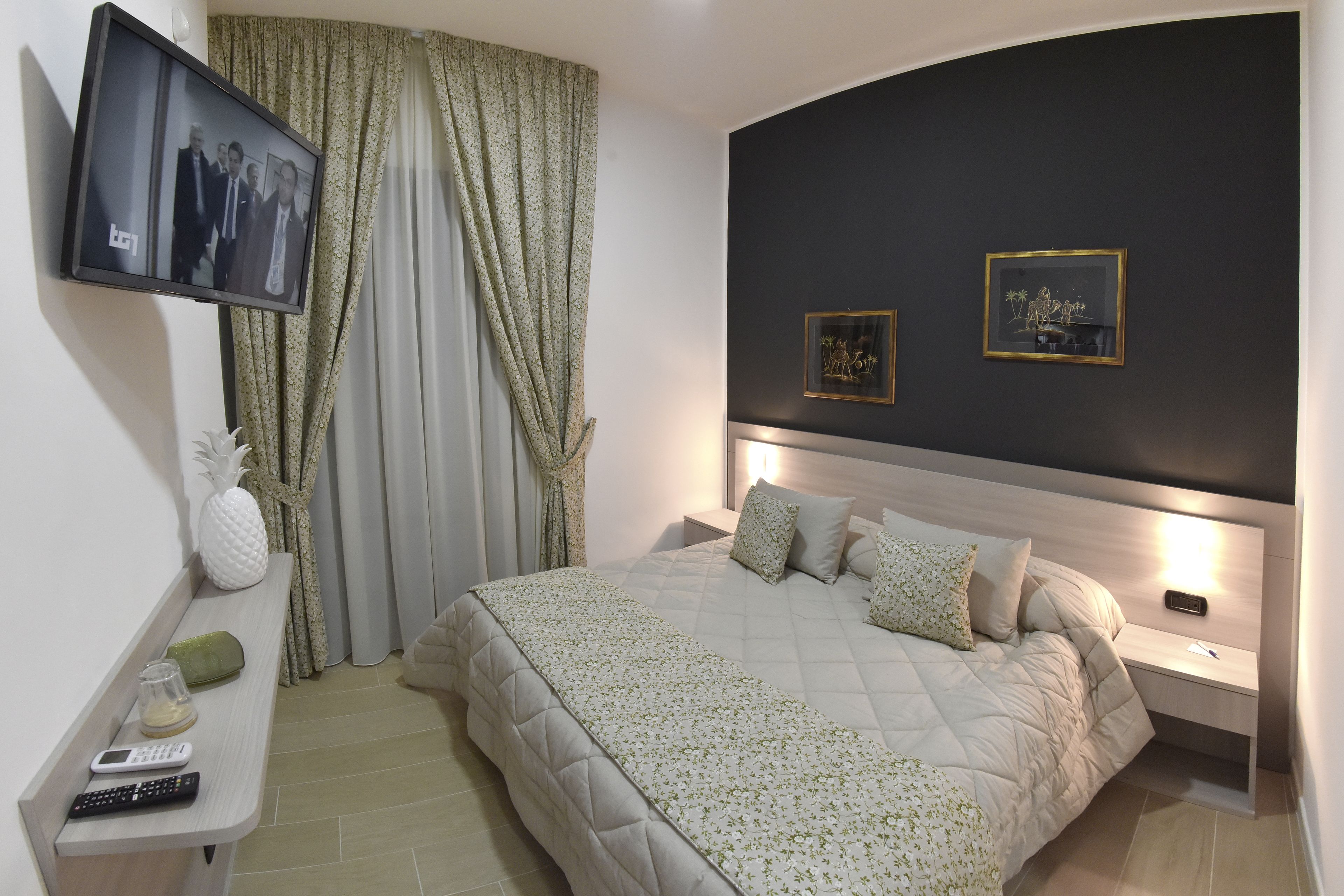 Quarto moderno com cama, mesas de cabeceira, televisão e quadro pendurado na parede.