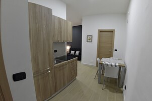 Cozinha compacta com armários de madeira, uma pia embutida e um espaço de jantar com toalha listrada.