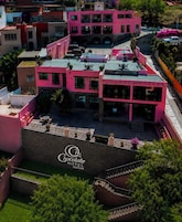 Um hotel com fachada rosa marcante, várias varandas e uma placa indicando ser o Chocolate Hotel Suites.