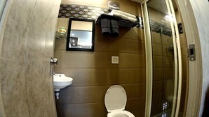 Casa de banho com sanita, lavatório e cabine de duche com parede de vidro.