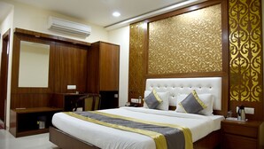 Quarto de hotel com uma cama grande, guarda-roupa de madeira e um painel decorativo na parede.
