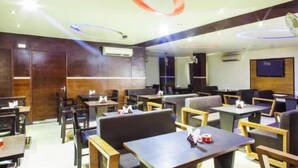 Um restaurante com cabines e mesas, painéis de madeira nas paredes e uma televisão de tela plana fixada na parede.