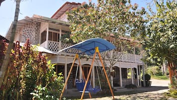 Uma casa de pedra com varanda, balanço e área de estar coberta.